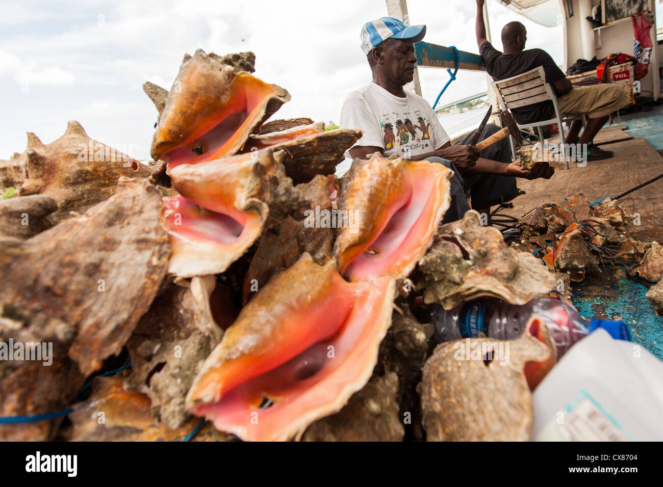 A fisherman cracks fresh conch at a roadside food stall at Potter's Cay ...