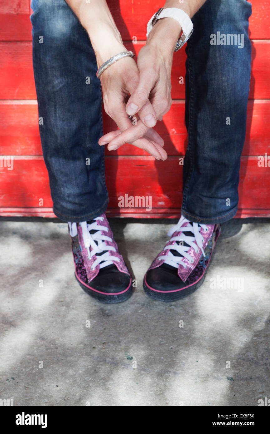 Woman sitting with her hands clasped and toes pointed inwards ...
