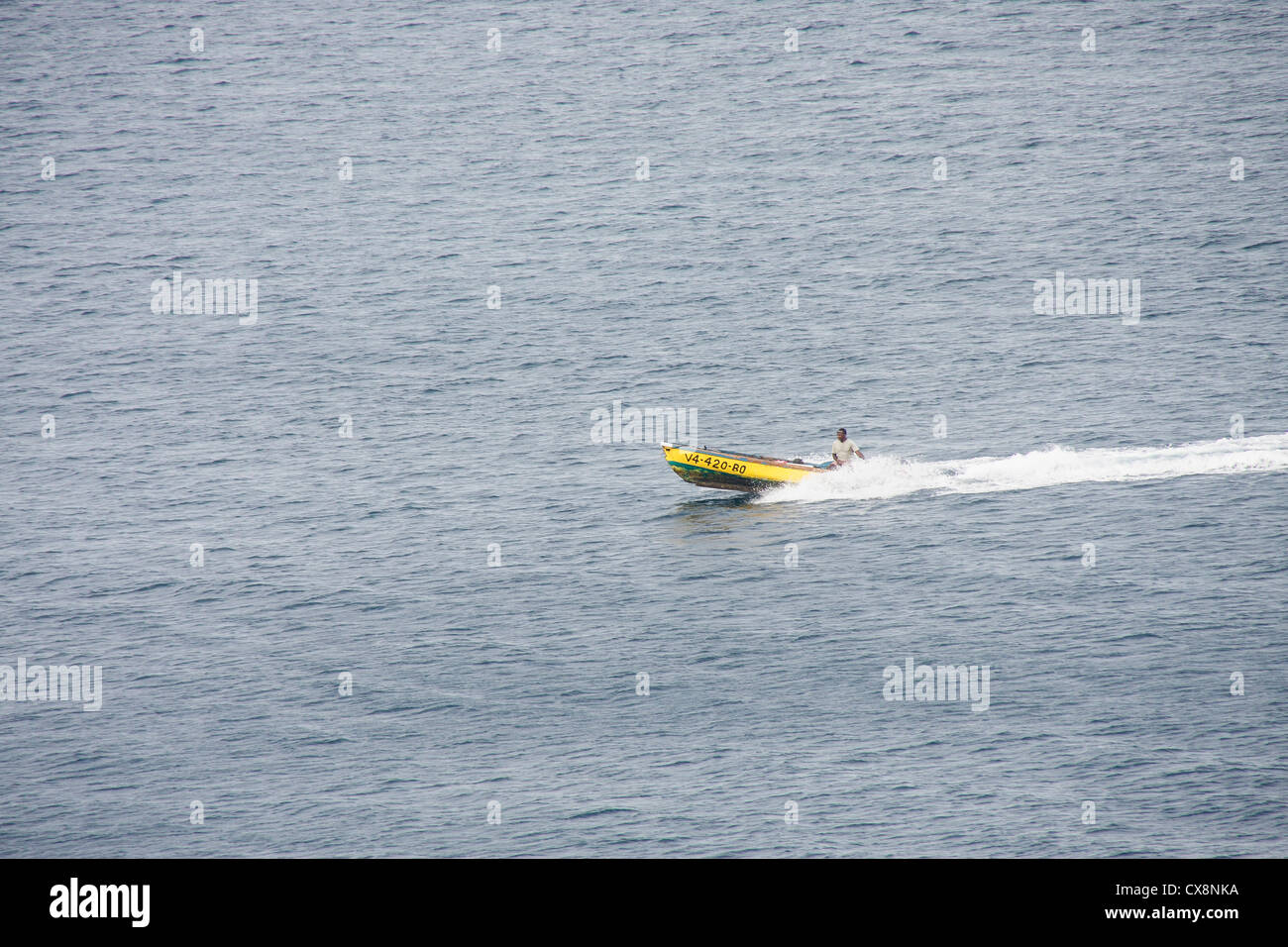 Man speeding across bay in a small yellow boat Stock Photo - Alamy