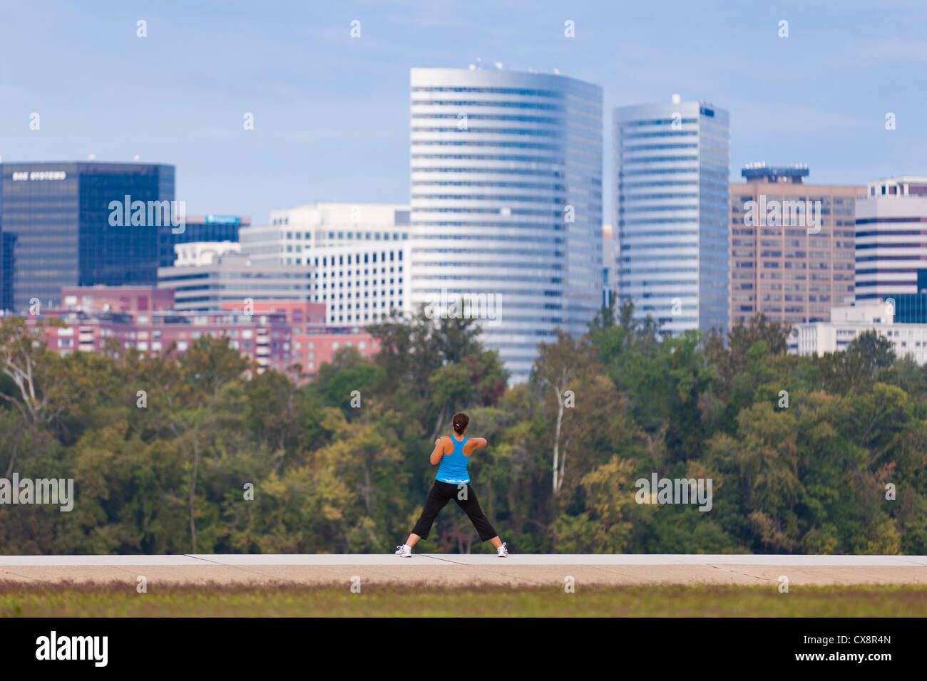 Woman stretching in park with urban scenery - Washington, DC USA Stock ...