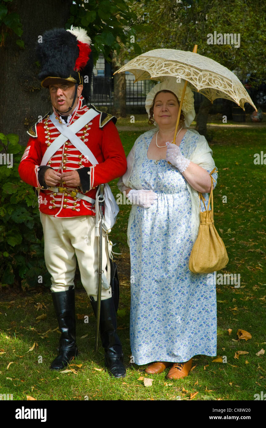 Red Coat soldiers in Regency uniform pose with lady in costume in park ...