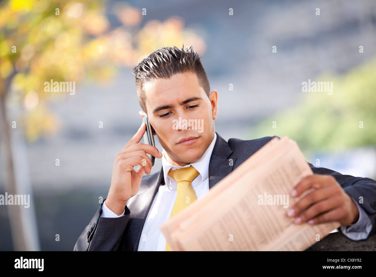 Businessman calling at the cellular and reading his newspaper Stock ...
