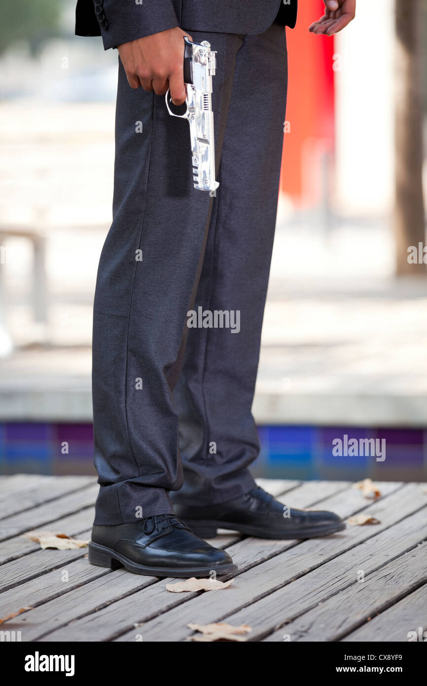 Businessman with a handgun aiming his own foot Stock Photo - Alamy