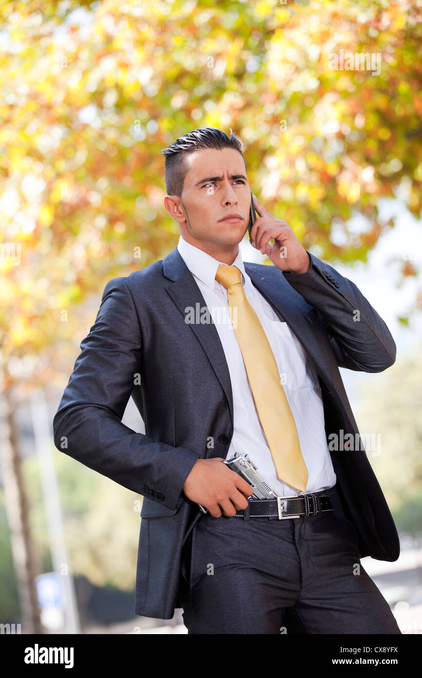 Powerful security businessman talking at his cellphone with a handgun ...