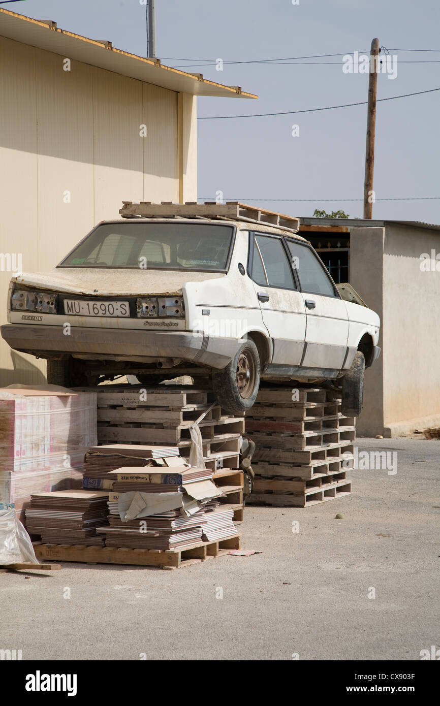 Old broken down car resting on a set of pallets outside a car garage ...