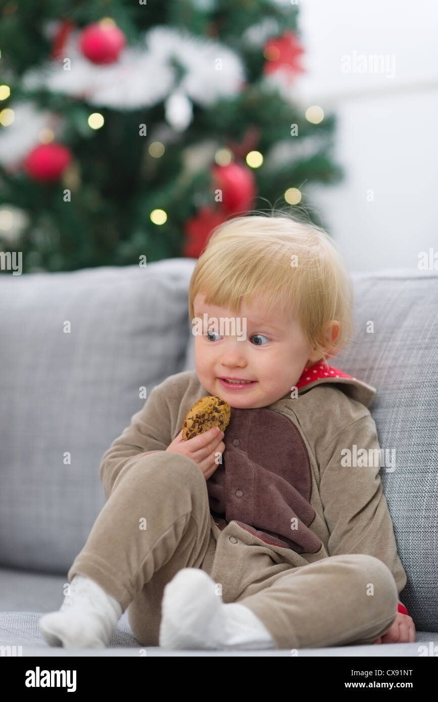 Scared baby in Christmas deer suit with cookie Stock Photo - Alamy
