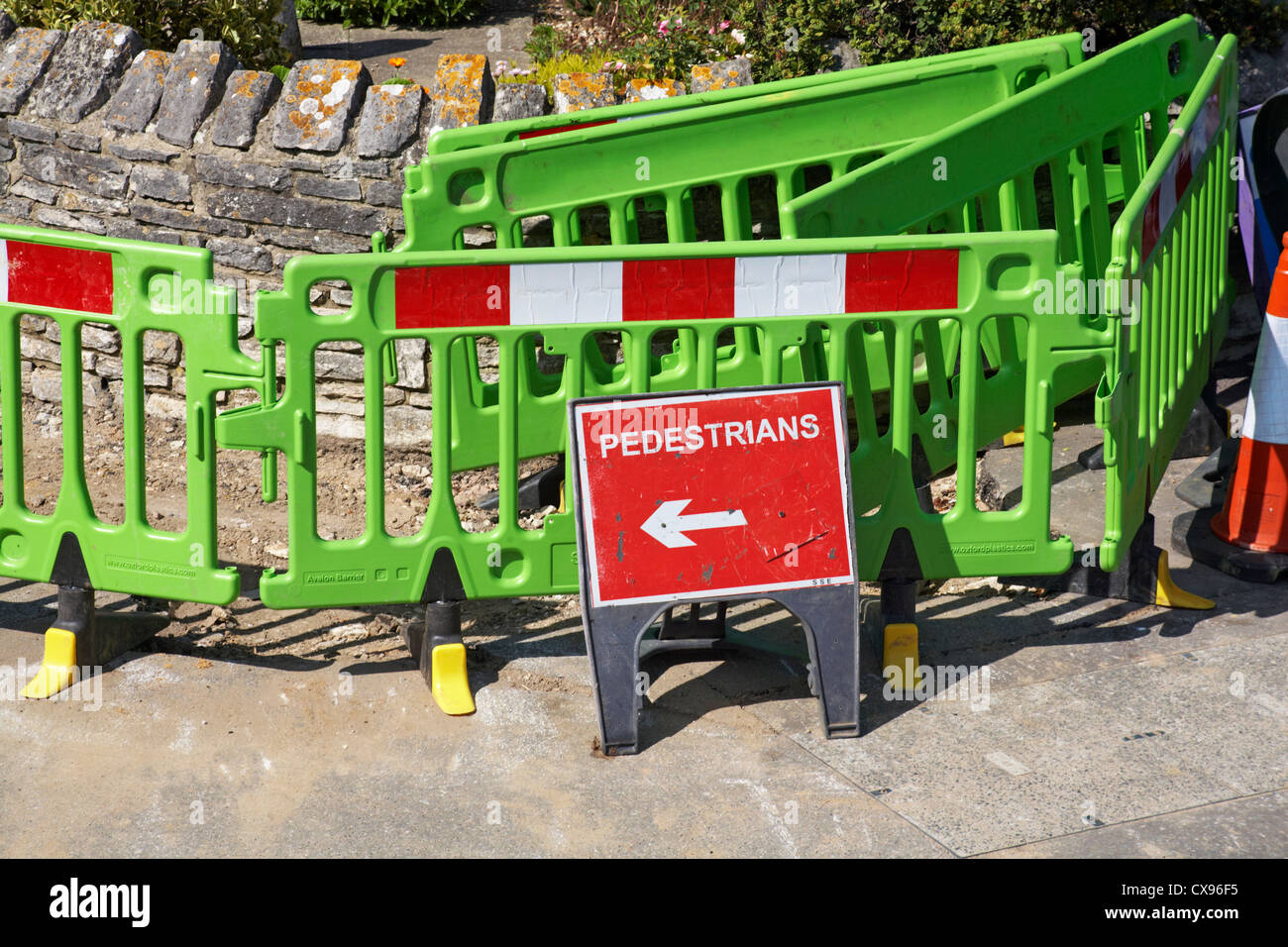 Pedestrians sign and bright green barriers diverting pedestrians around ...