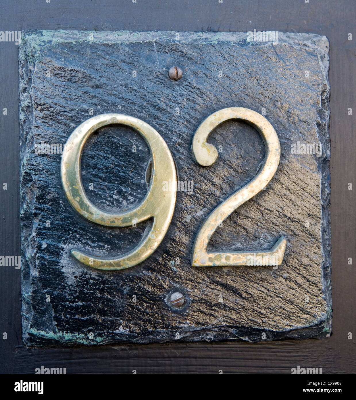 Number 92 on black slate with gold polished brass finish hi-res stock ...