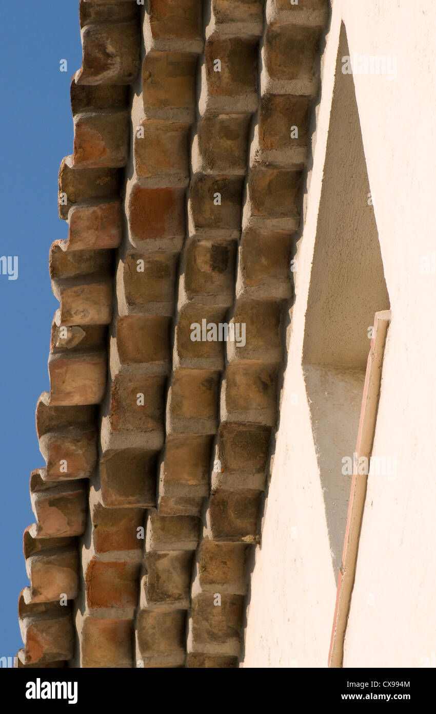 The underside of four rows of roof tiles project from the side of a ...