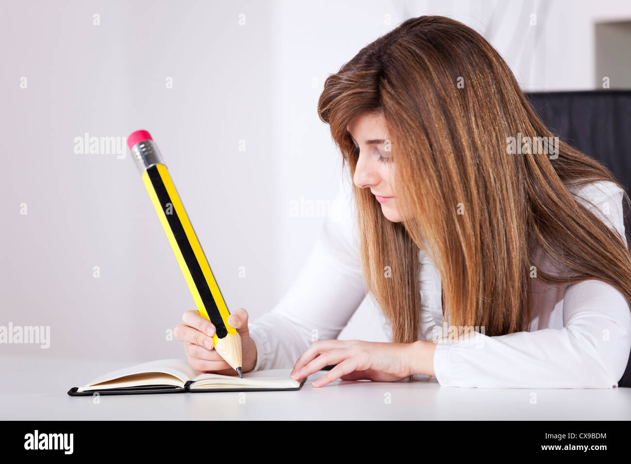 Businesswoman taking some notes on her notepad with a giant pencil ...