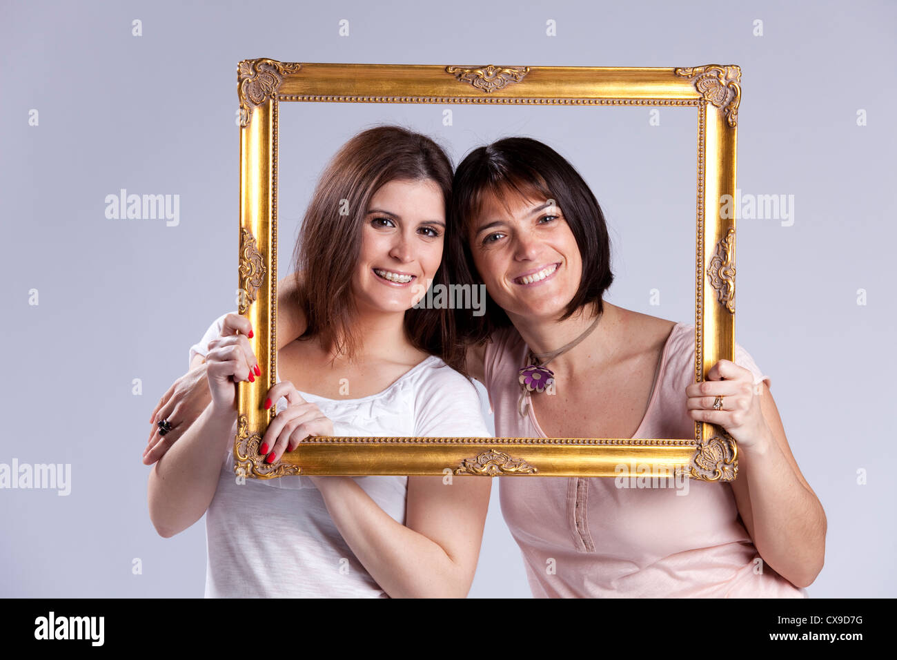 two beautiful woman inside an antique picture frame (isolated on gray ...