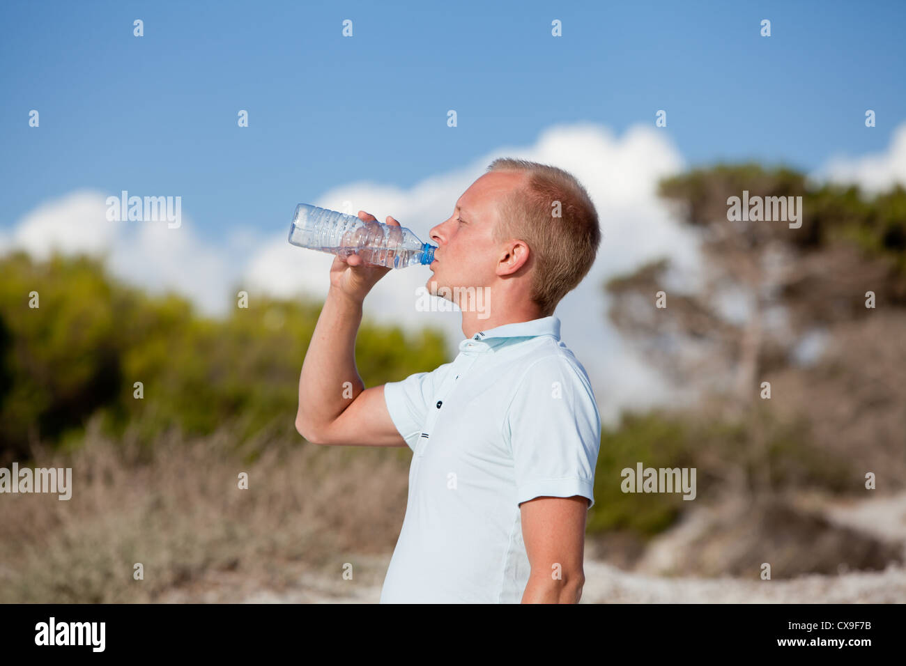 young man ist drinking water summertime dune beach sky background Stock ...