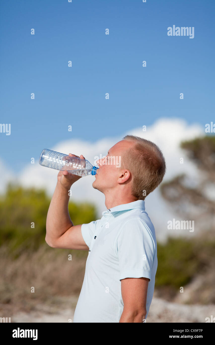 young man ist drinking water summertime dune beach sky background Stock ...