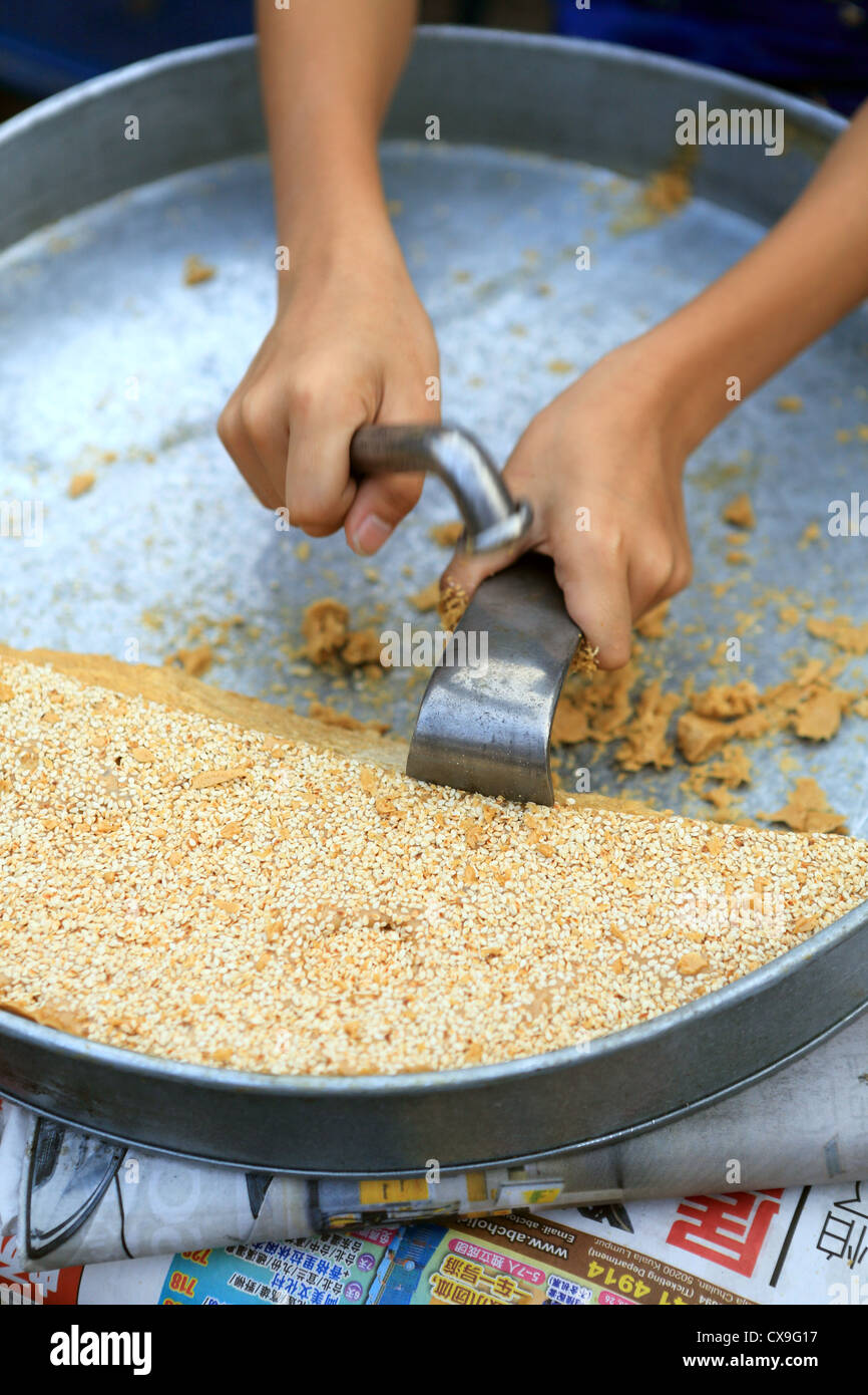 A boy chips pieces off a large hard toffee candy block at the Jonker ...