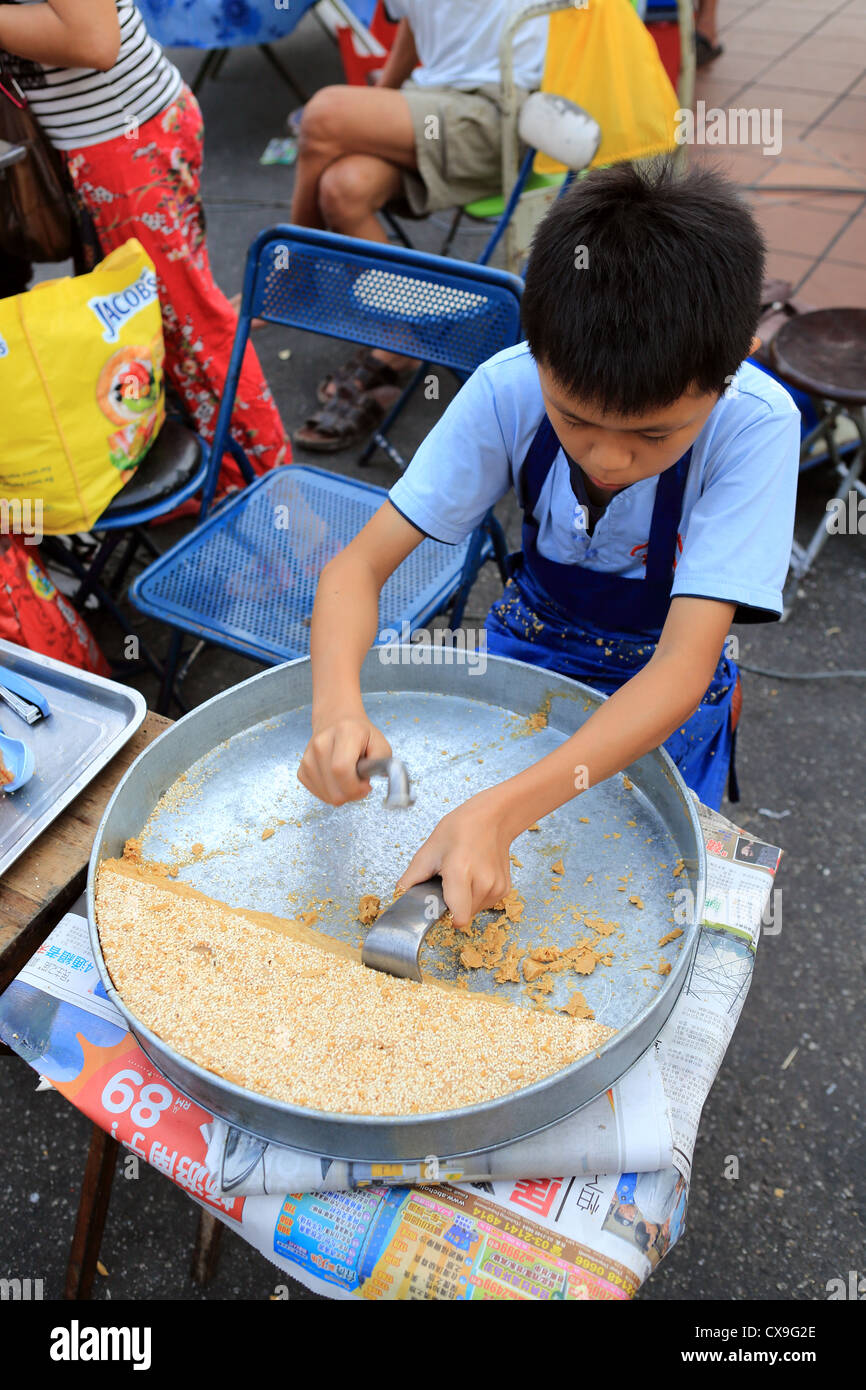 A boy chips pieces off a large hard toffee candy block at the Jonker ...