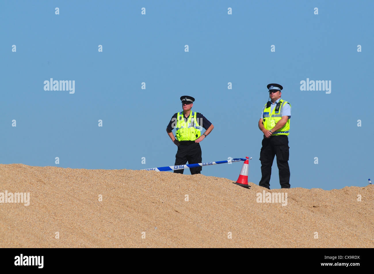 Two police officers with a cordon round an incident on a Dorset beach ...