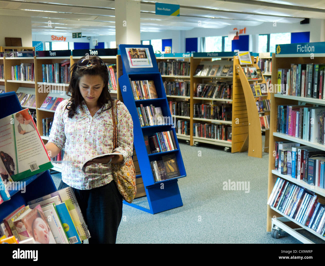 Woman browsing books in a public library interior Stock Photo - Alamy