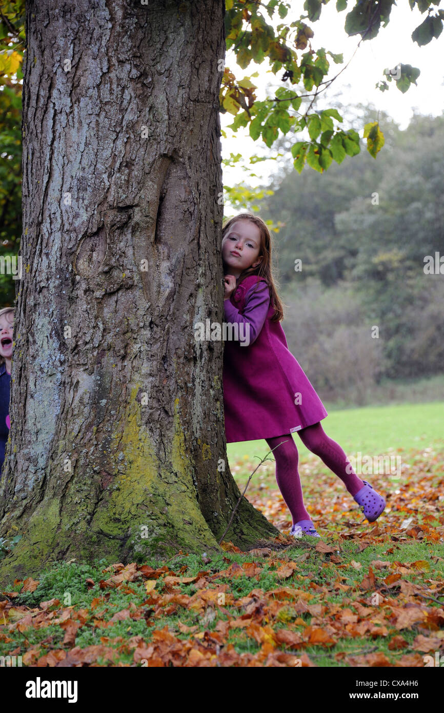 Young Girls Peeks Out From Behind A Tree During A Game Of Hide And Seek