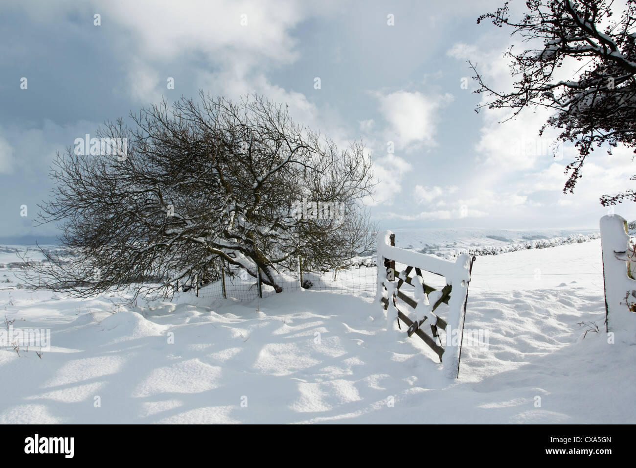Winter view of snow covered moors, looking through an open gate and ...