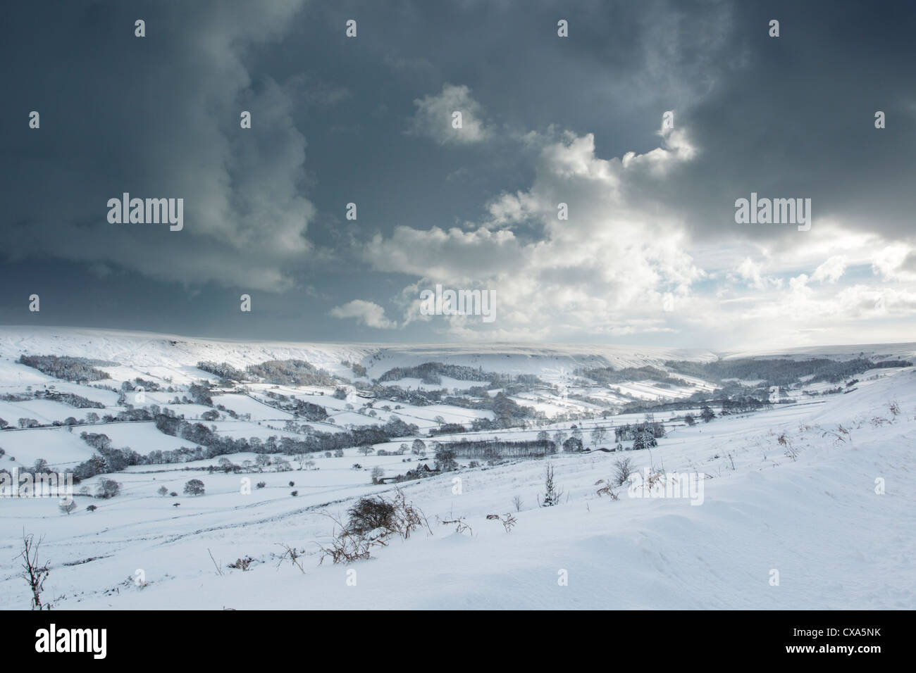 Winter view of a gathering storm over snow covered moors, looking into ...