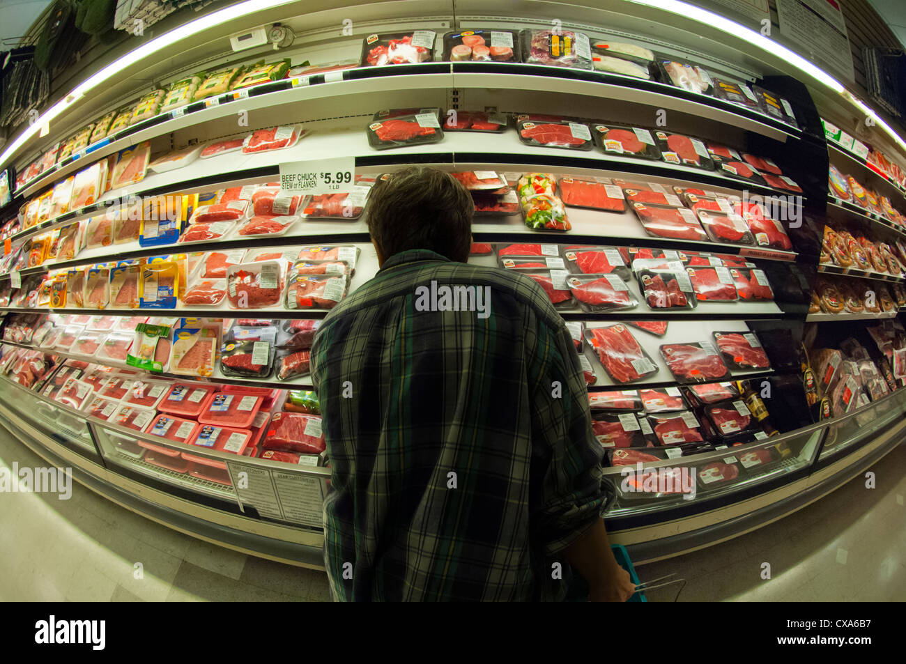 A shopper chooses a cut of meat in the butcher department in a ...