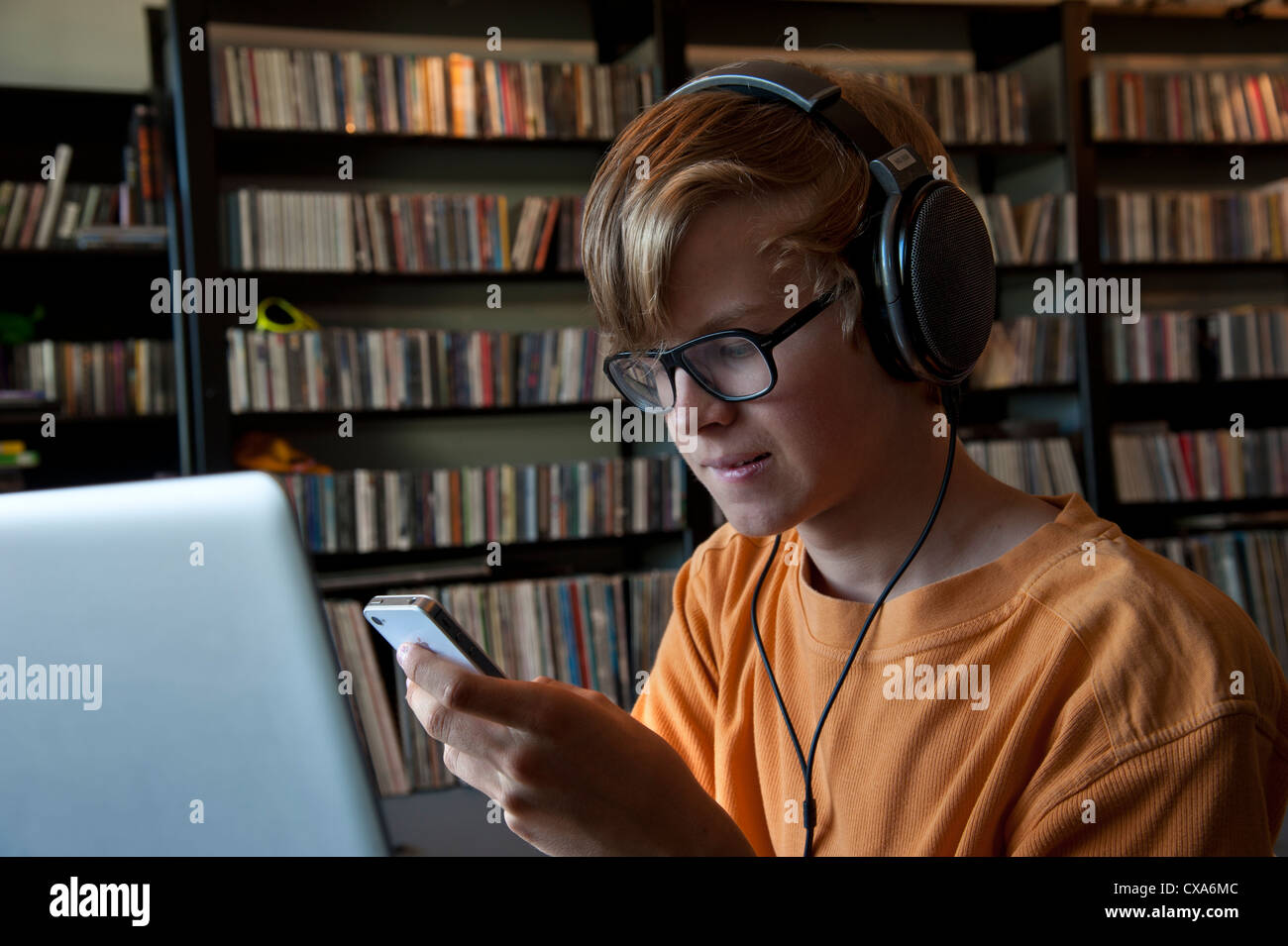 Studious teenage school boy wearing headphones using his Apple iPhone ...