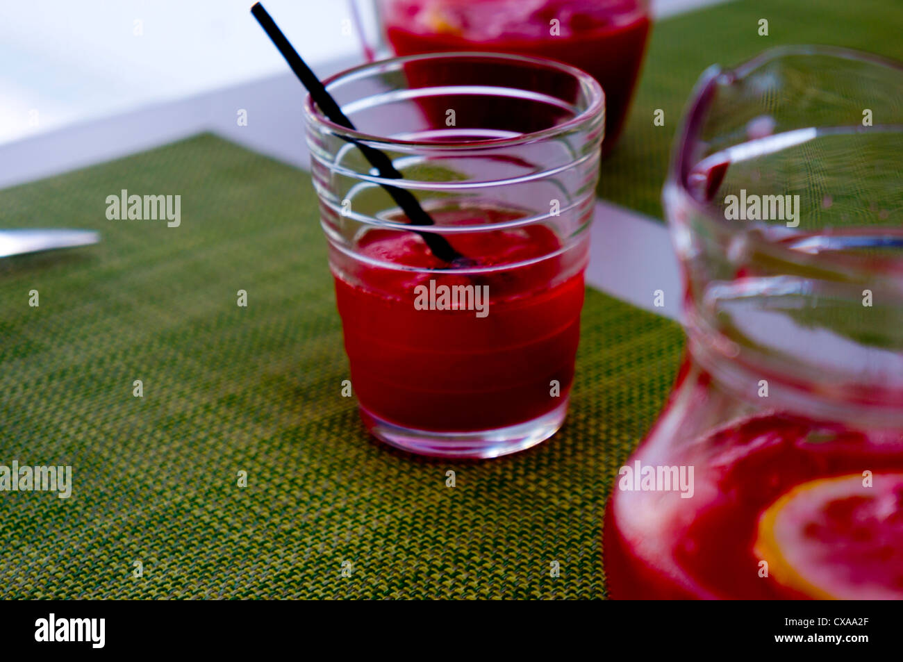 A stylish, ringed glass containing a red coloured punch and a straw ...