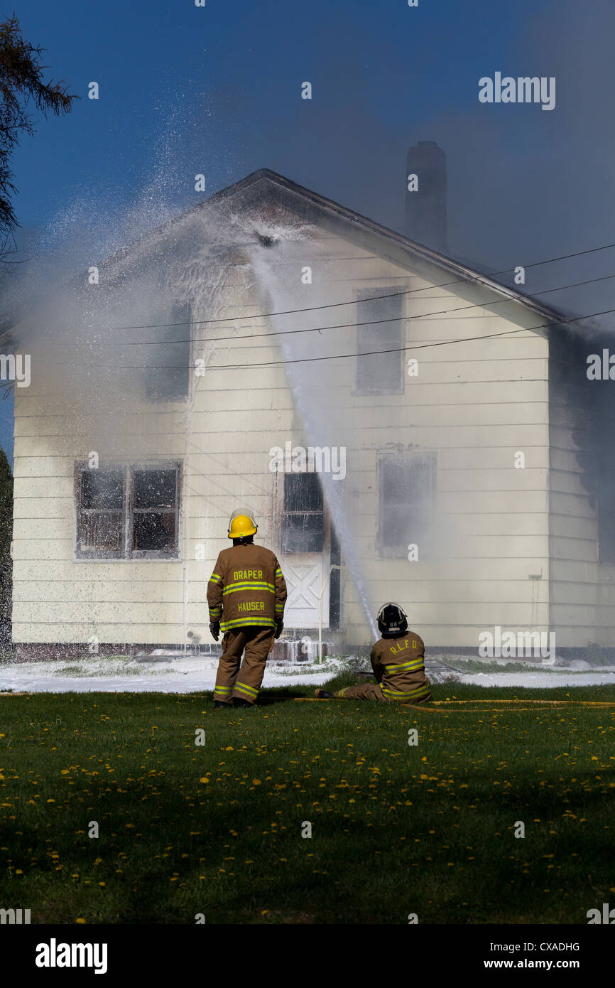 Volunteer firefighters fighting a house fire Stock Photo - Alamy