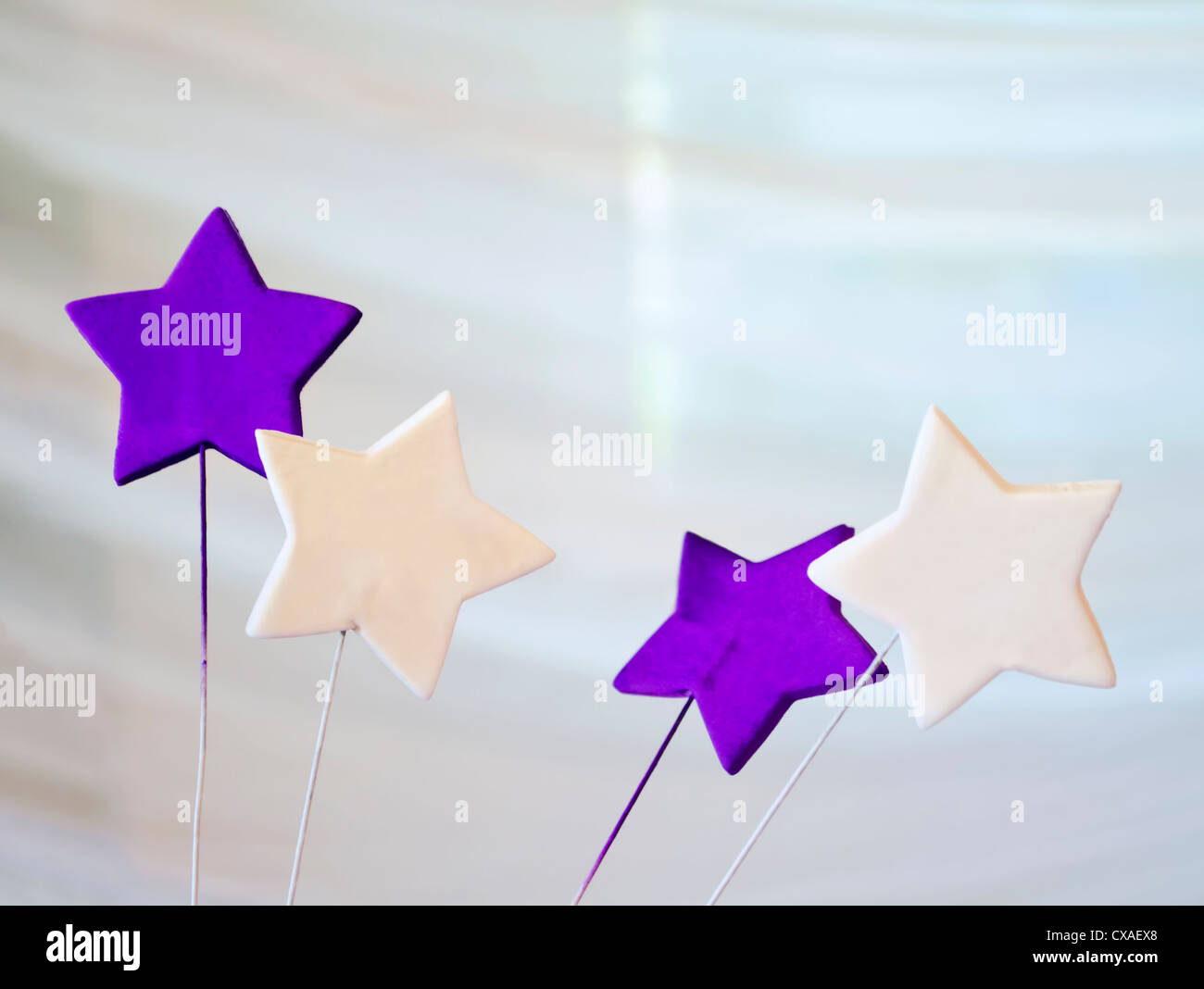 Four purple and white star-shaped cake toppings Stock Photo - Alamy