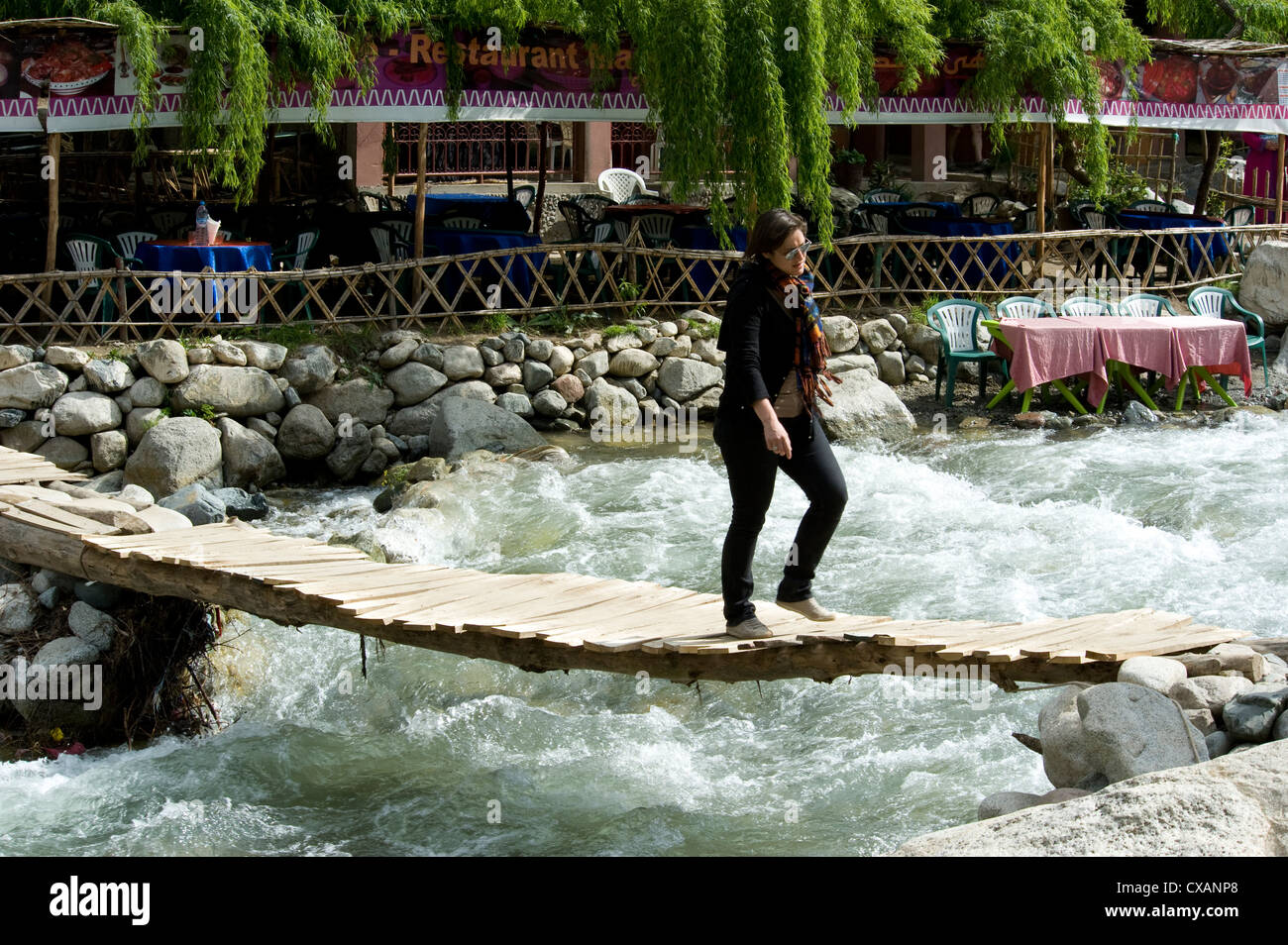 Crossing over a raging river on a precarious wooden slatted bridge in ...