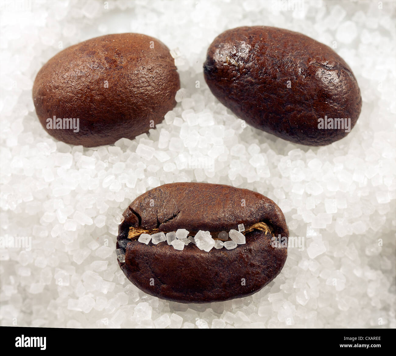 a closeup of three coffee beans on a bed of sugar, arranged as a smile ...