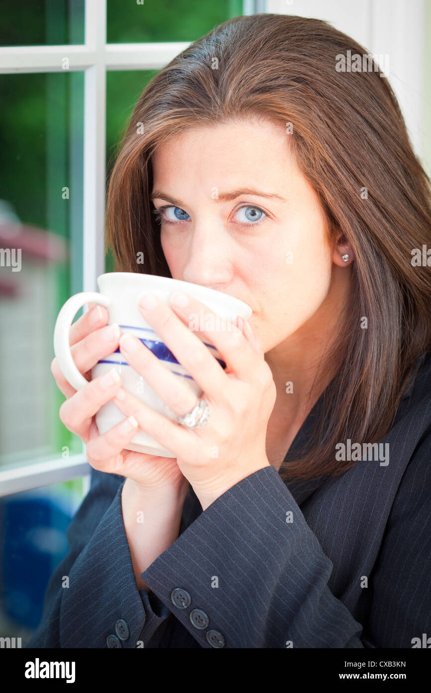 Pretty adult woman sipping drink with sad expression Stock Photo - Alamy