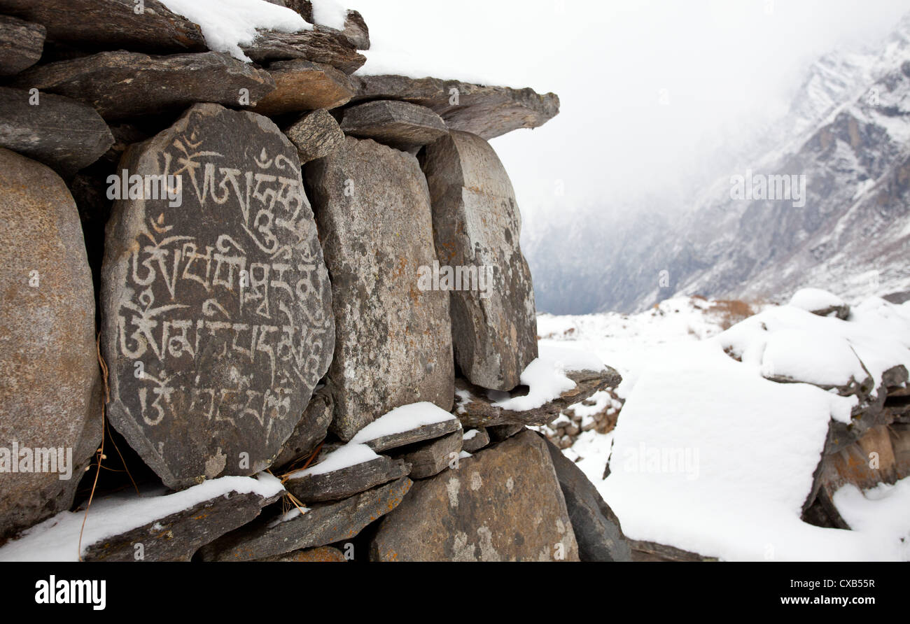 Old Mani Stones inscribed with a Buddhist mantra and covered with snow ...