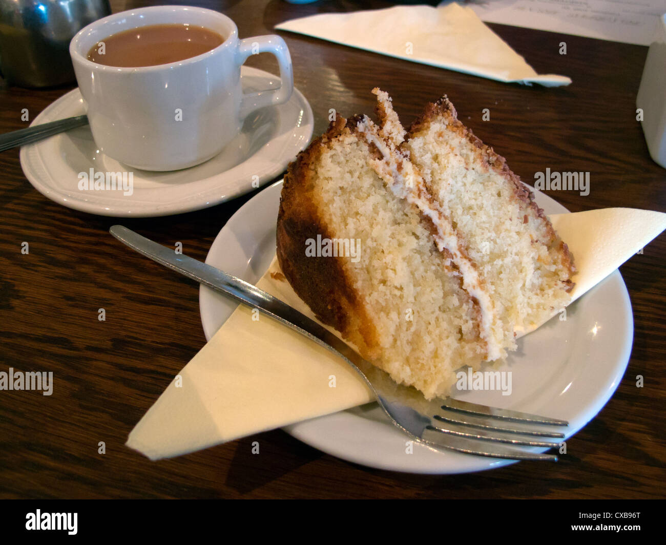 Slice of Victoria sponge cake on a plate with cup of tea in the ...