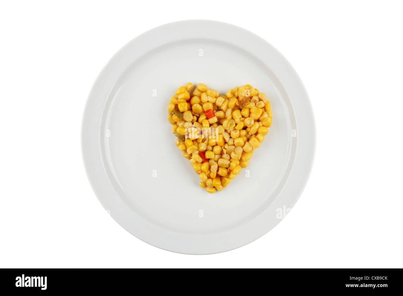 Sweetcorn and peppers in a heart shape on a plate isolated against ...