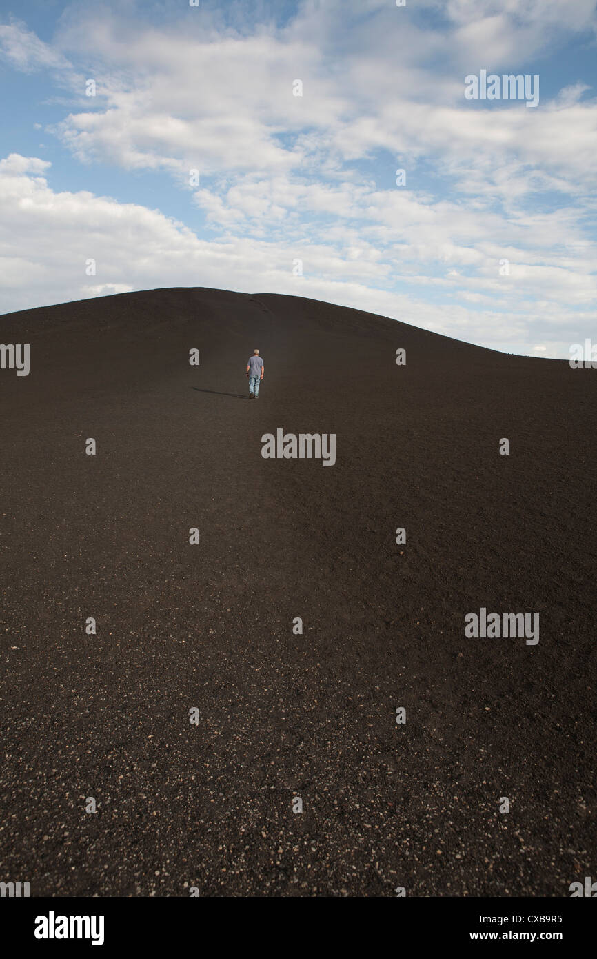 A visitor climbs Inferno Cone, a cinder cone, at Craters of the Moon ...