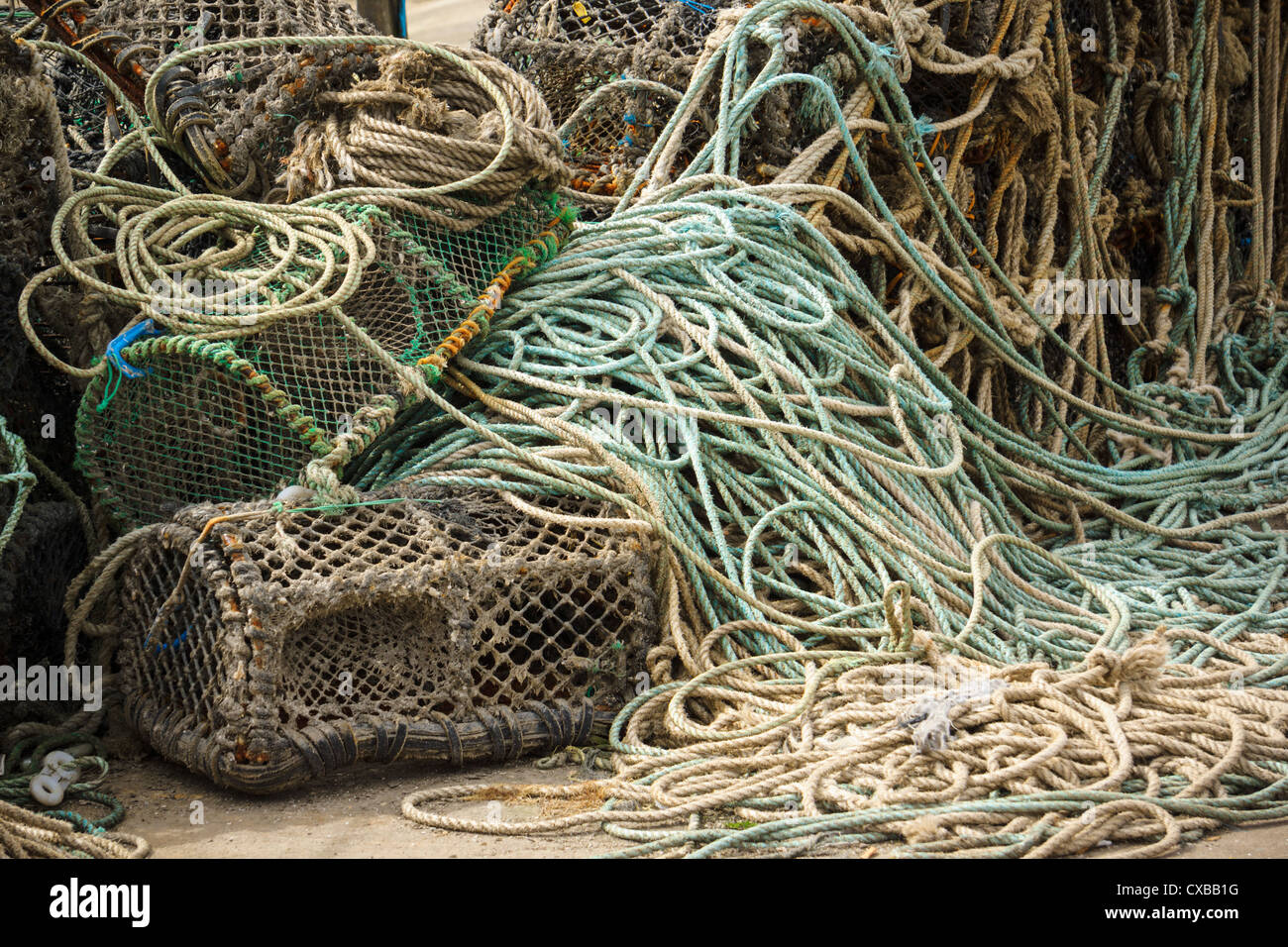 A pile of fishing ropes, lobster and crab pots on the harbour wall at ...