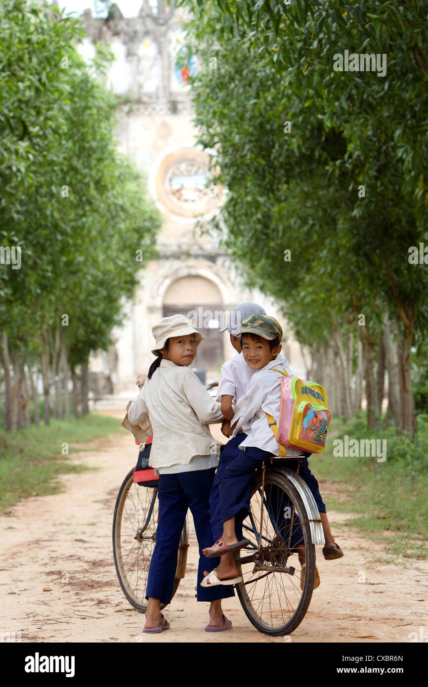 Vietnam, Vietnamese children on a bicycle surrounded by tree-lined ...