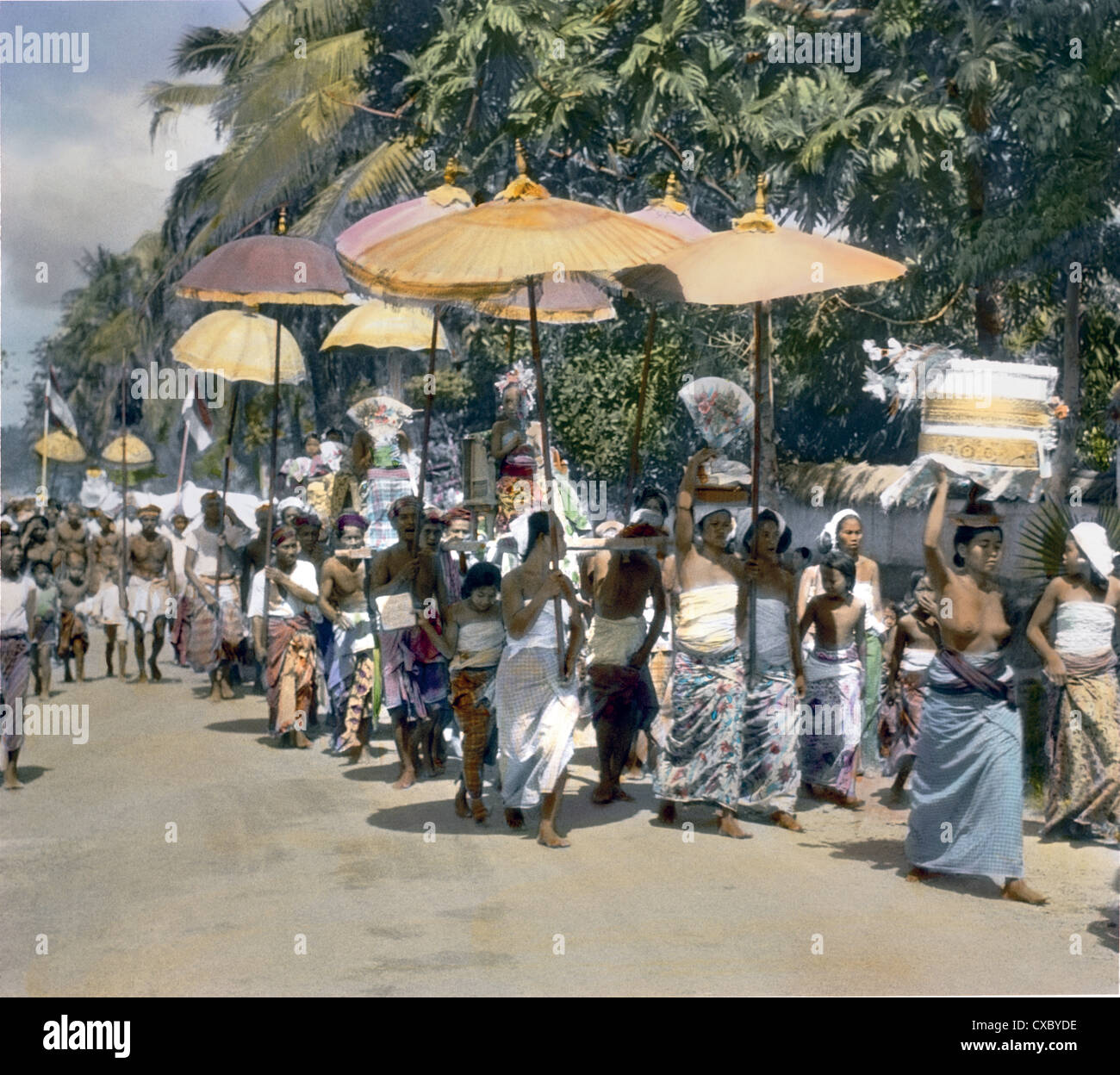 Colorized photo of Javanese men, women and children carrying parasols ...