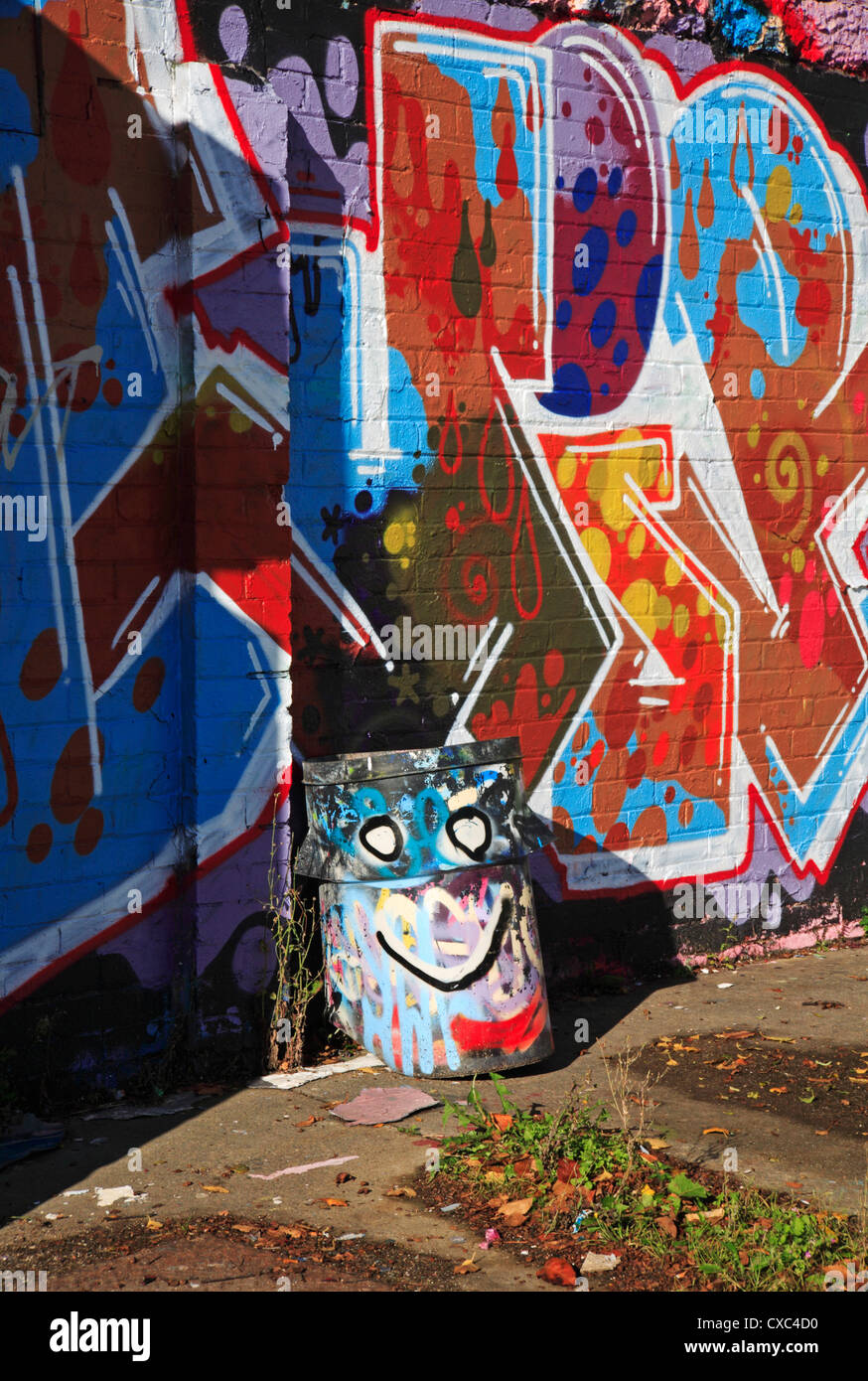 A graffiti covered wall with a decorated bin in a derelict area in ...