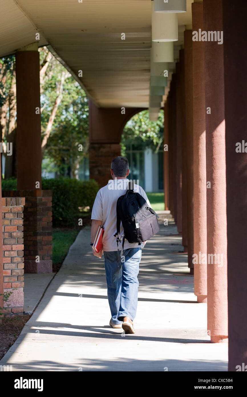 Middle aged student walks down an outdoor walkway to class on a college ...