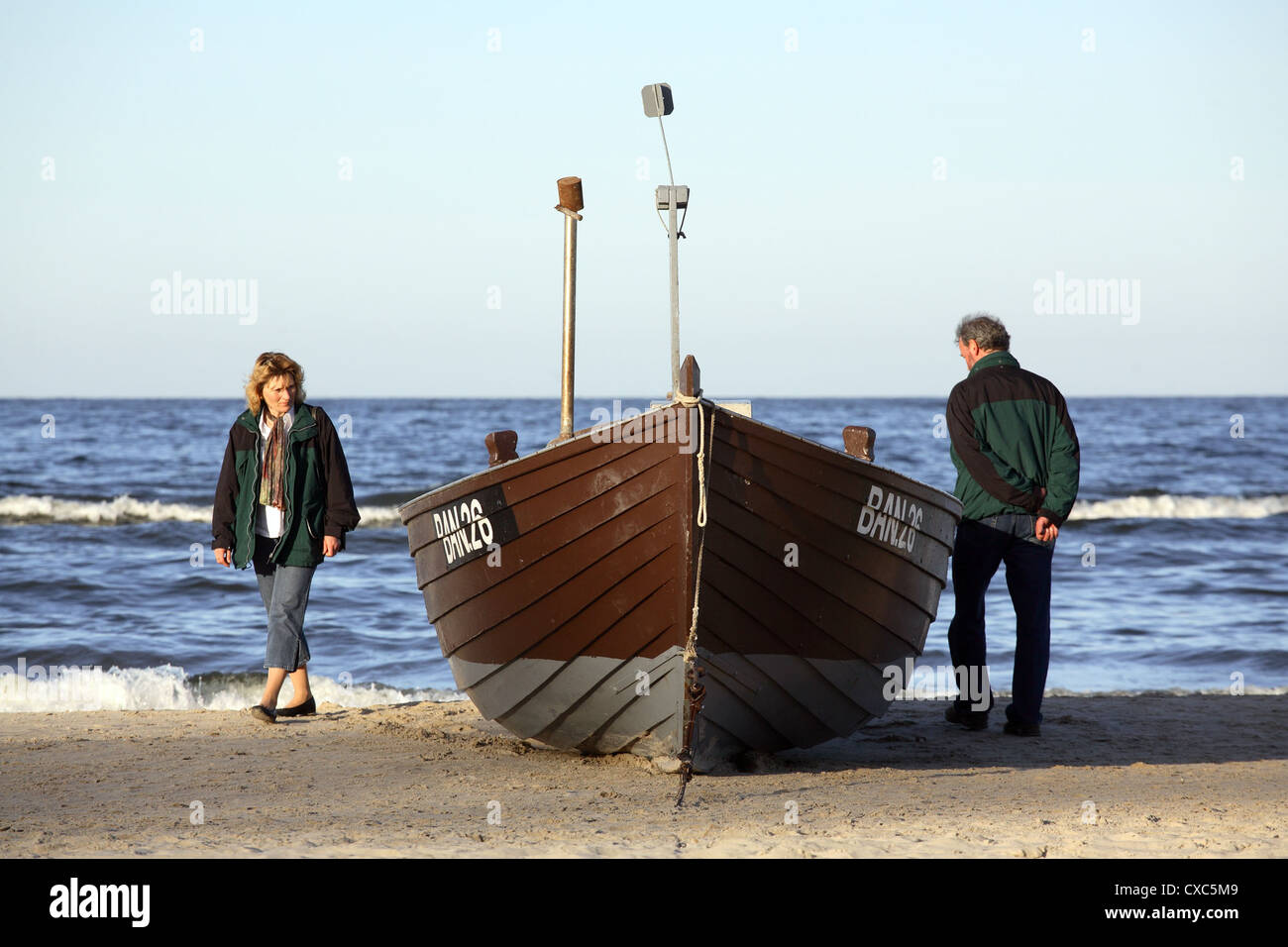 Walkers and fishing boat on the beach Stock Photo - Alamy