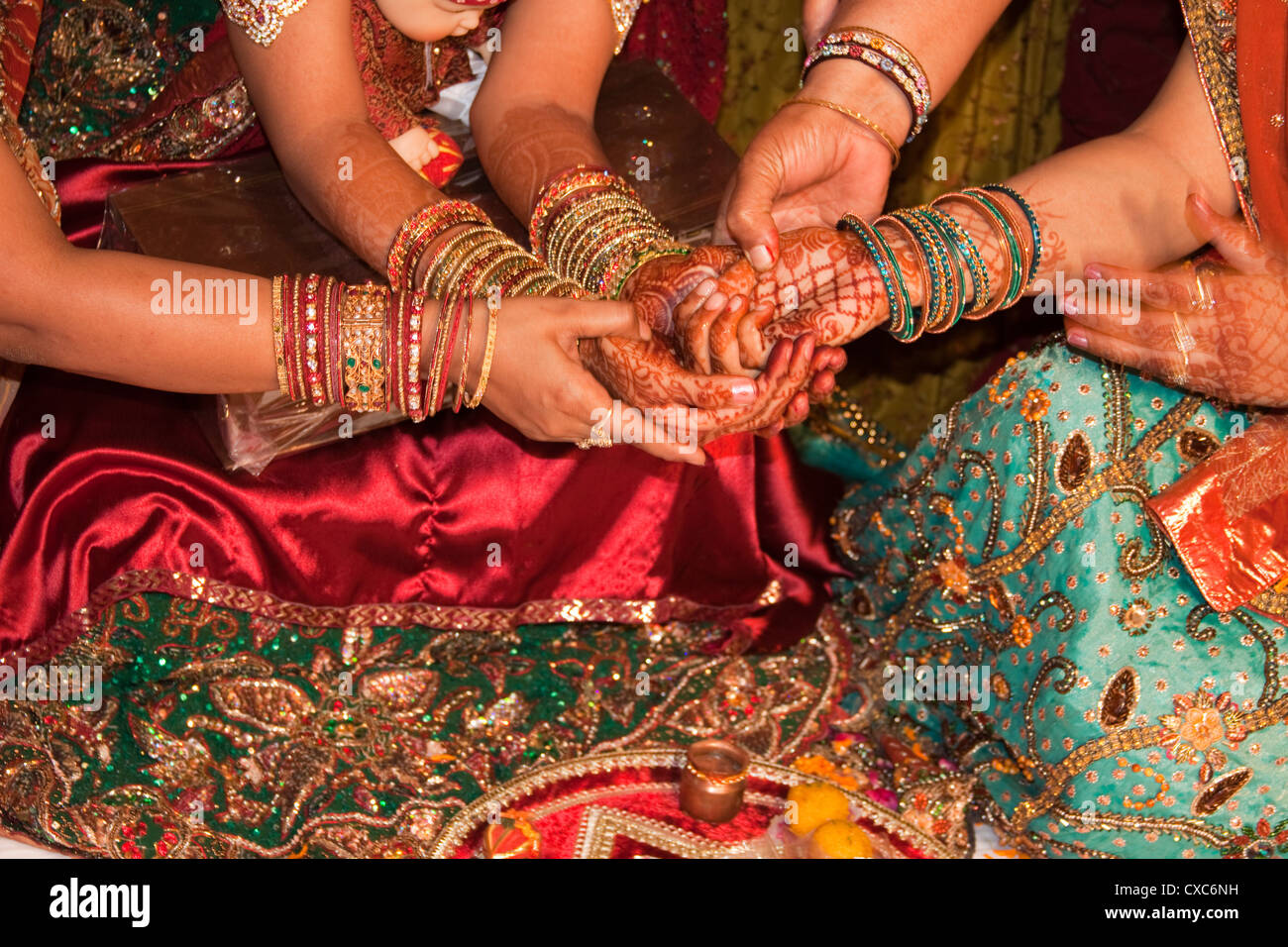 Women with decorated hands, bangles, holding hands in a Hindu religious ...