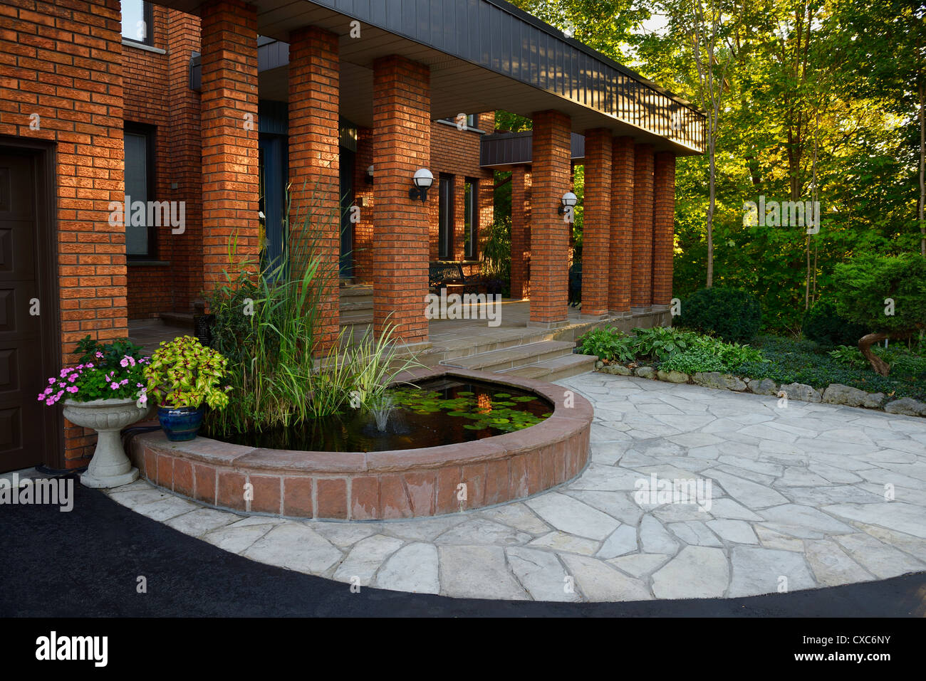 Front entrance with pond and stone veranda on red brick house with ...