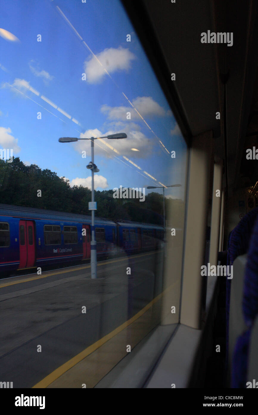 a view through a traveling train window of another train and a platform ...