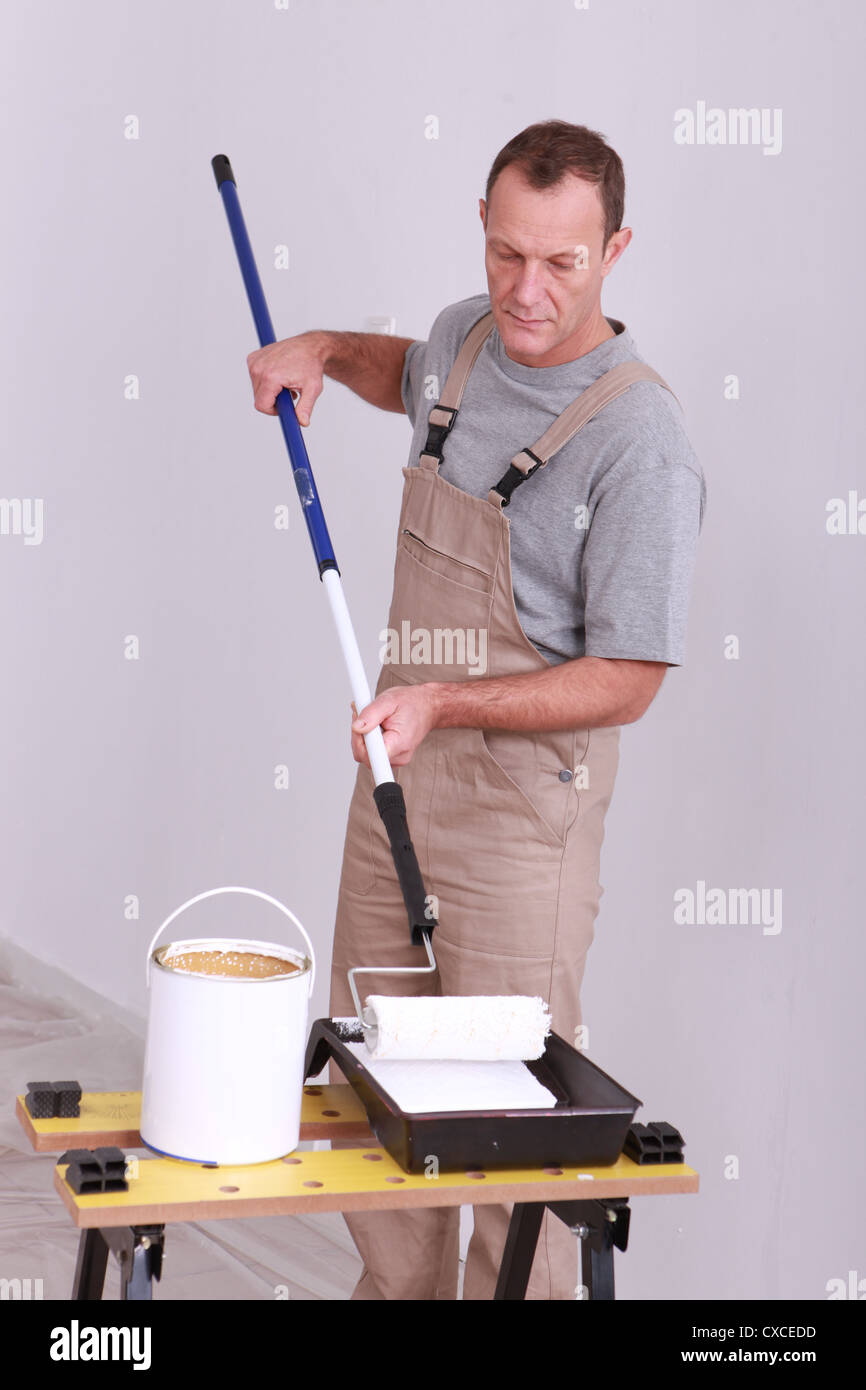 Man applying paint to roller Stock Photo - Alamy
