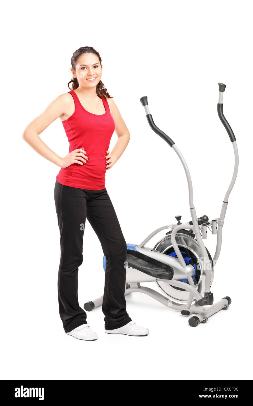 Young female posing next to a cross trainer isolated on white ...