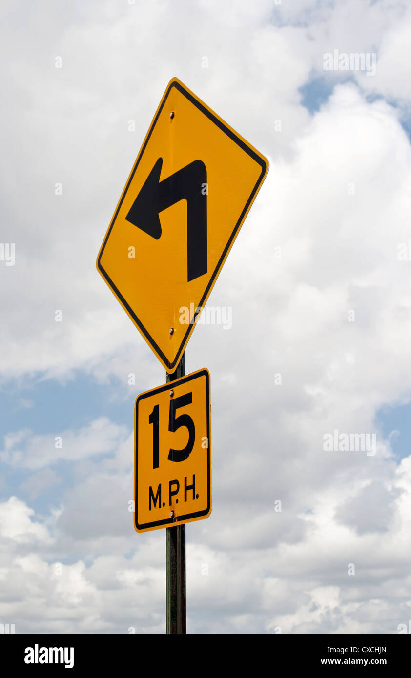 Yellow road sign with turn arrow against blue cloudy sky Stock Photo ...
