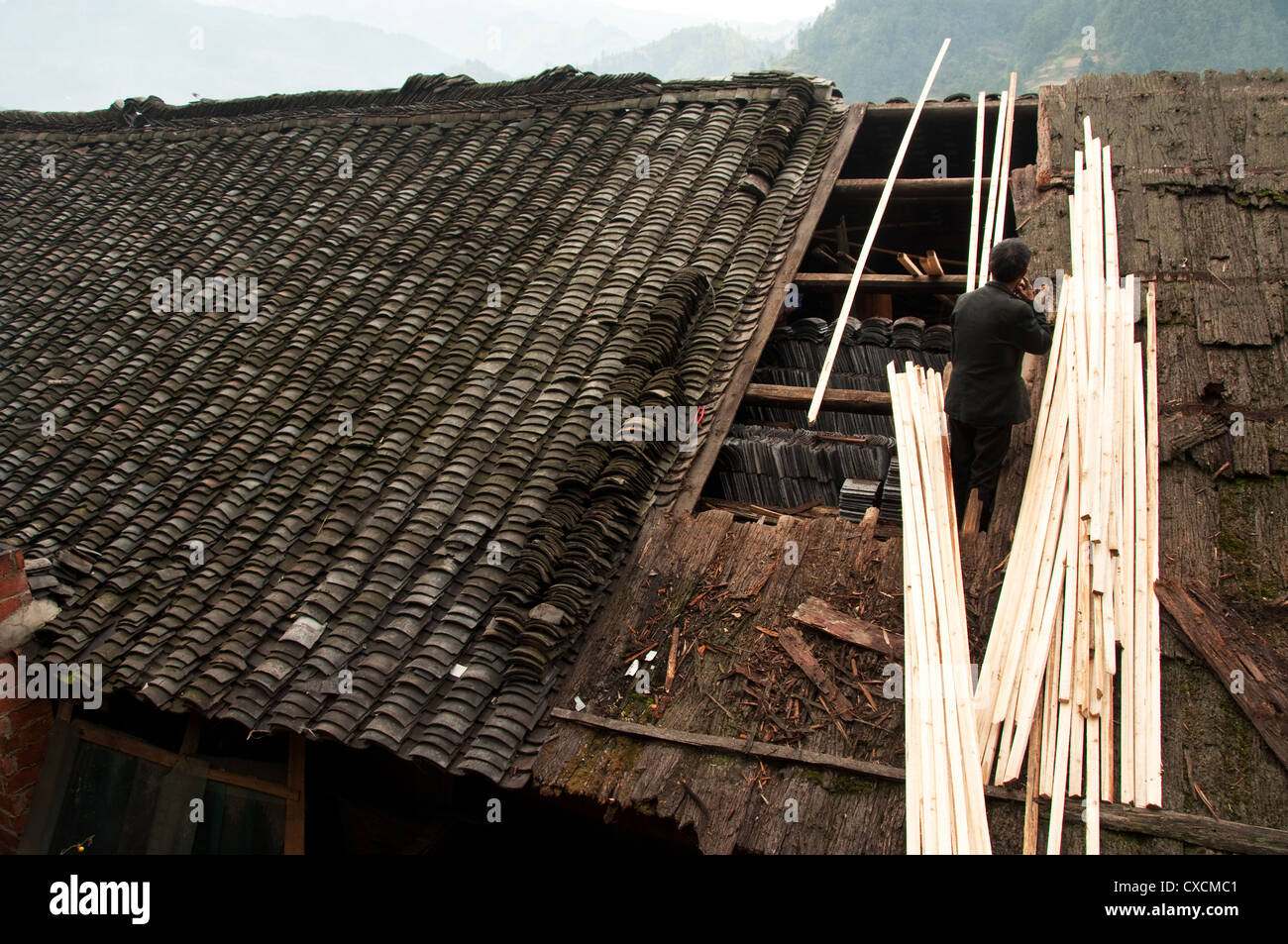 A man repairing the roof of a traditional Miao house Stock Photo - Alamy