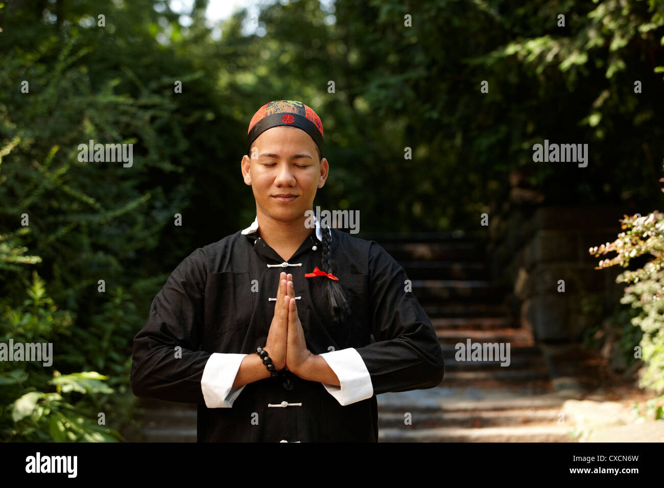 Man in traditional Asian clothing praying Stock Photo - Alamy